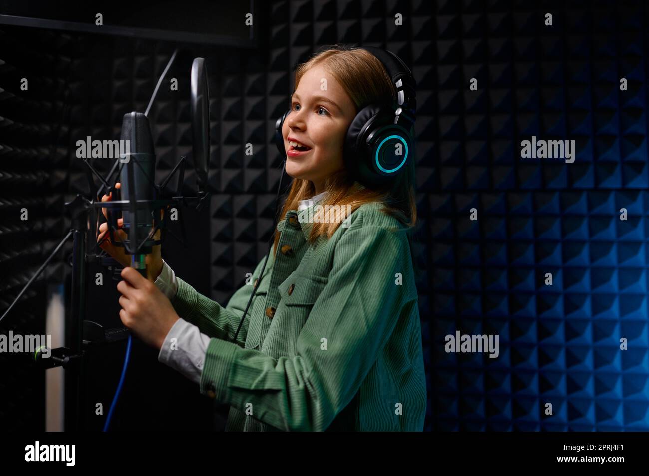 Young teenager girl star singer wearing headphones singing new song ...