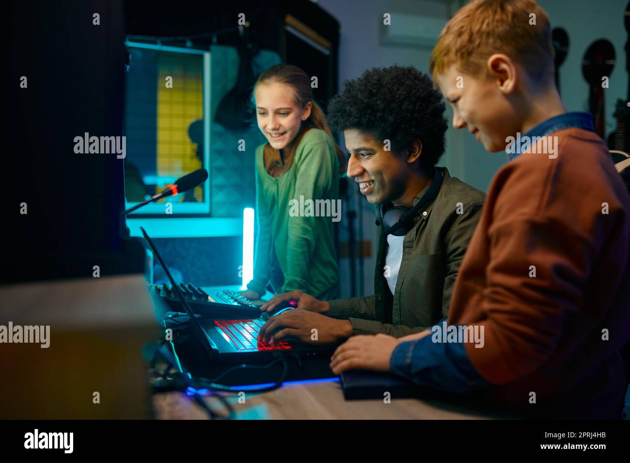 Sound producer mixing track with children band on laptop computer in ...