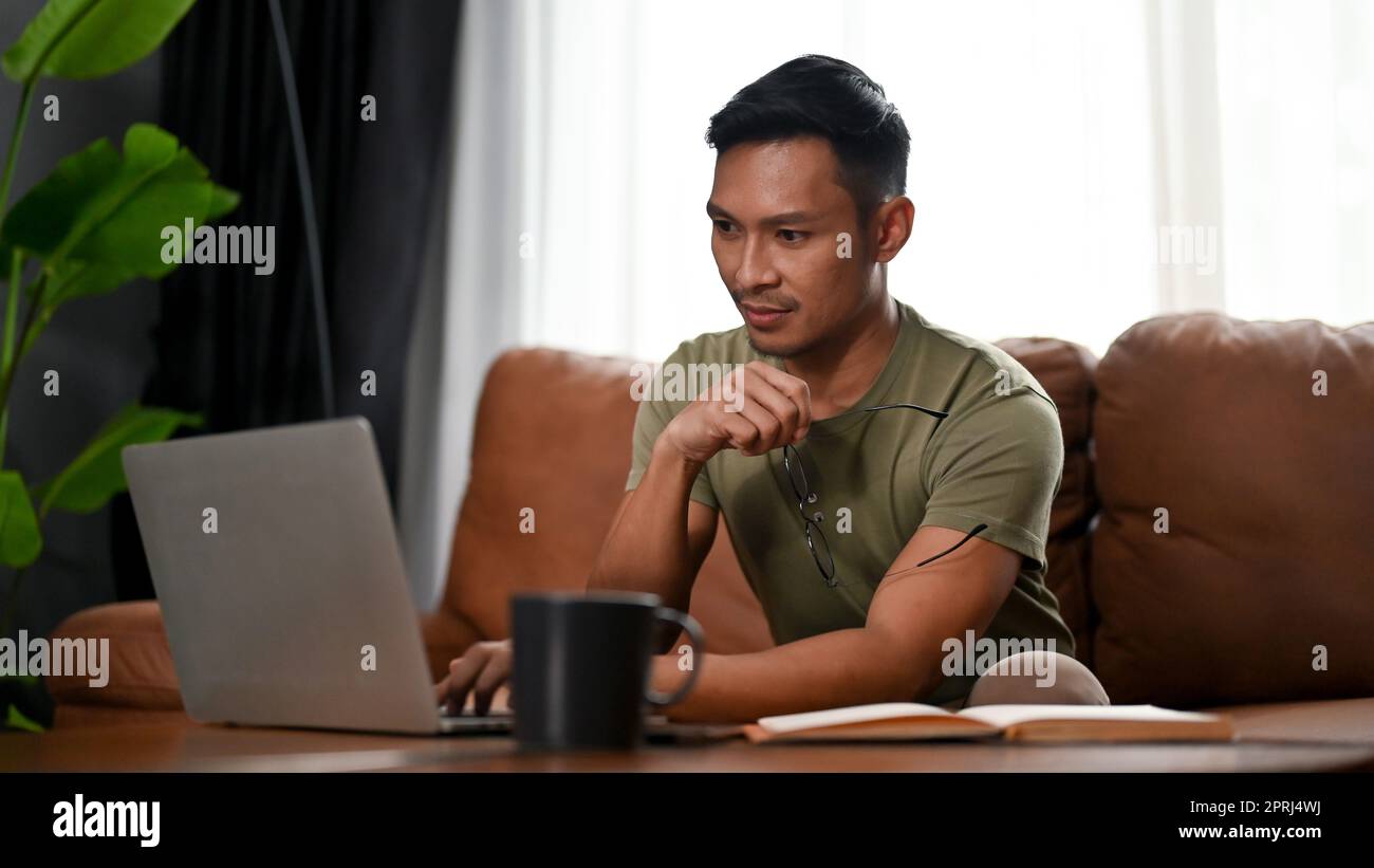 Focused and smart millennial Asian man looking at his laptop screen ...
