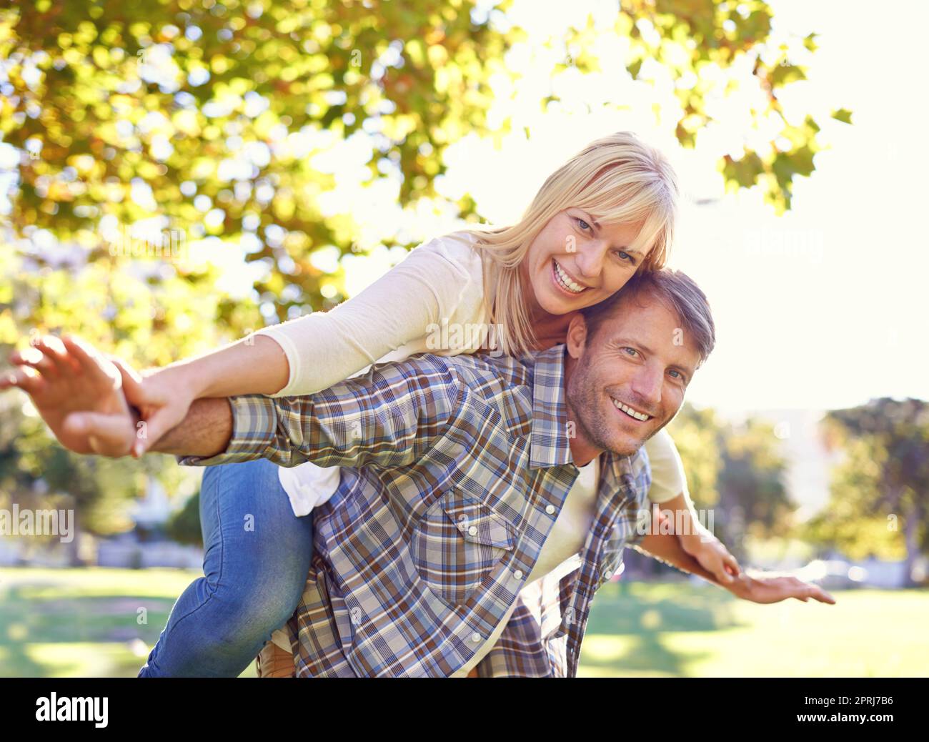 Love makes you act like kids again. a happy man piggybacking his wife ...
