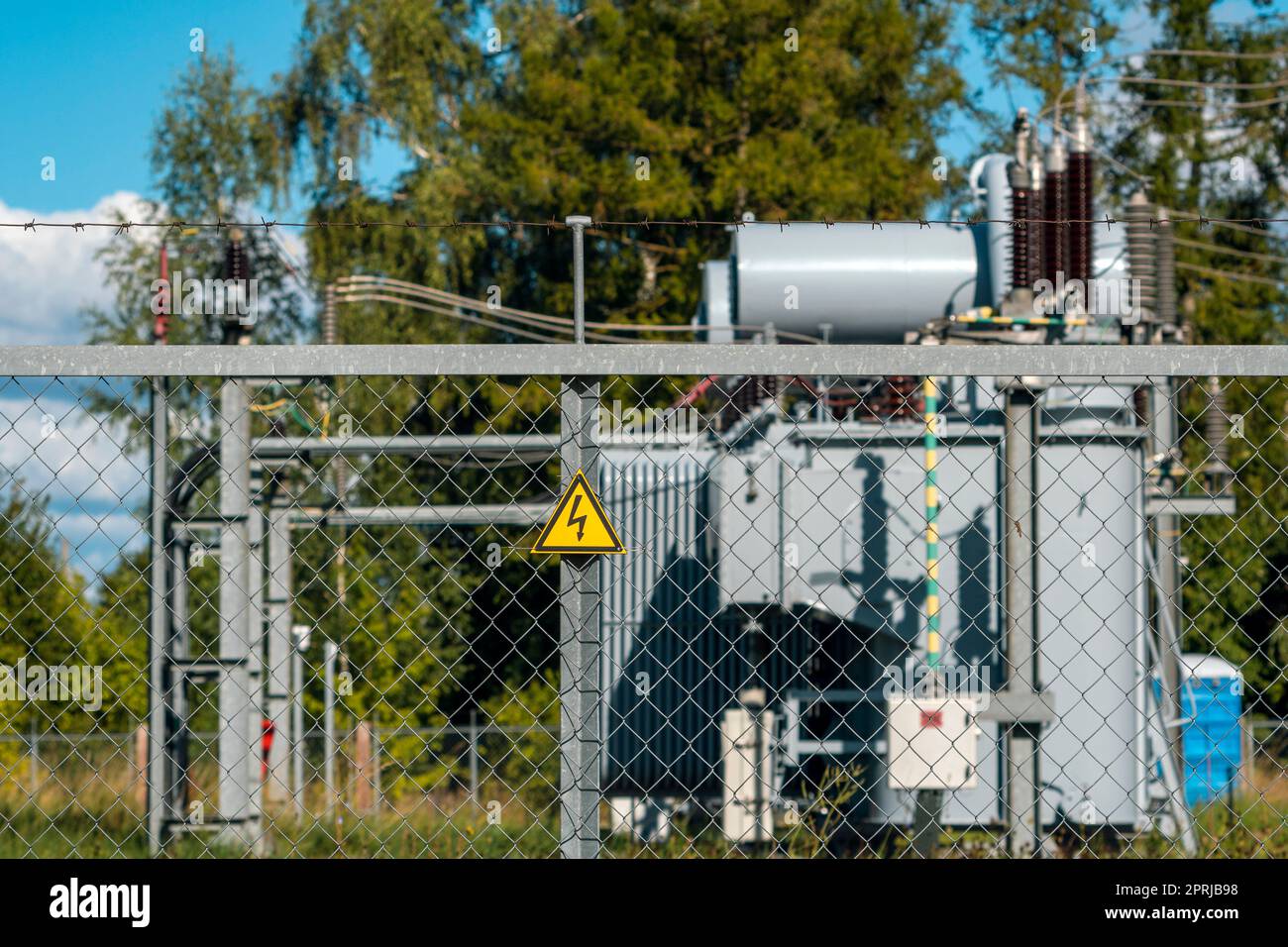 High voltage electrical substation behind metal mesh fence Stock Photo ...