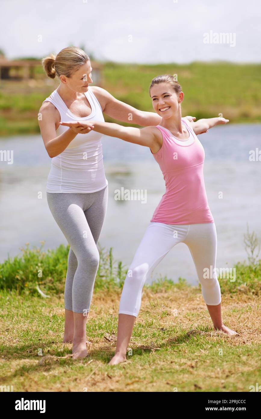 Grounding herself. a young woman being instructed in an outdoor yoga ...
