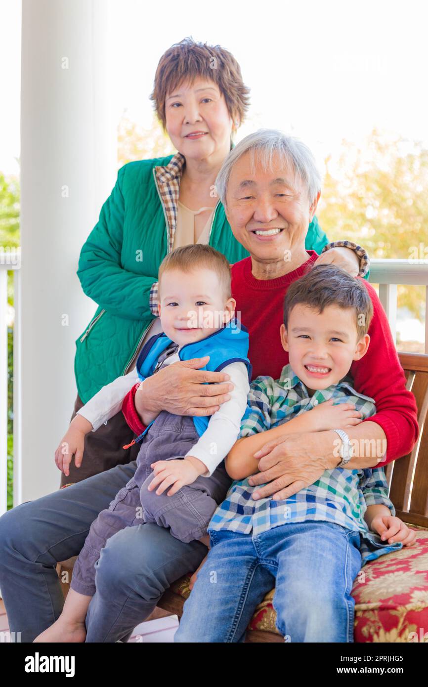 Senior Adult Chinese Couple Sitting With Their Mixed Race Grandchildren ...