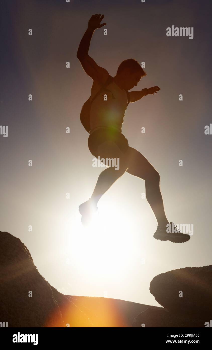 Be bold and take risks. A silhouette of a man jumping over rocks Stock ...