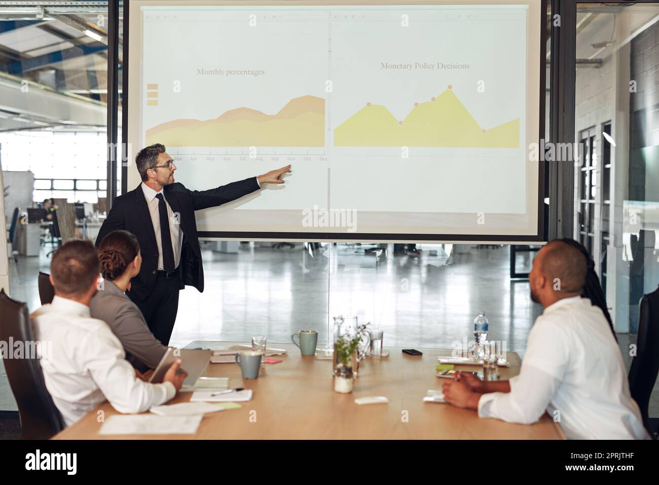 Comparing facts and figures. an executive giving a presentation on a projection screen to a ...