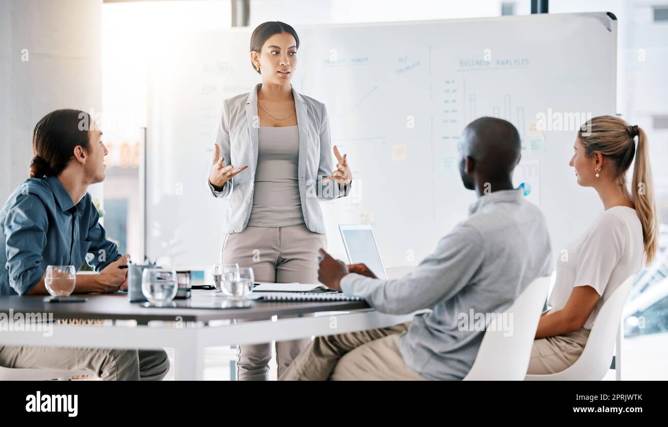 Corporate manager planning a project on a whiteboard with her team doing research in modern ...