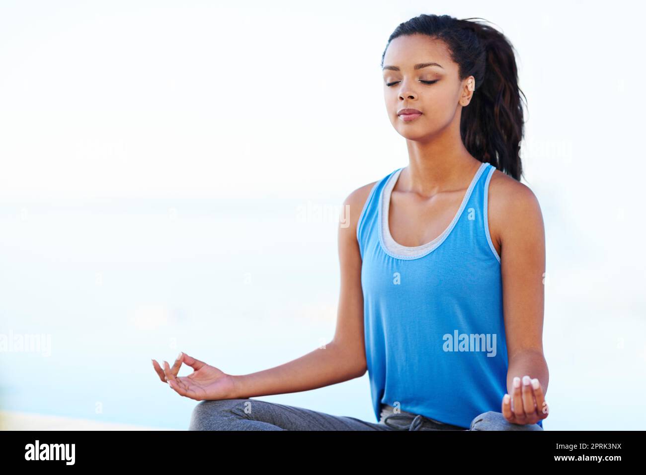 Getting her inner fitness on. a young woman sitting in the lotus ...