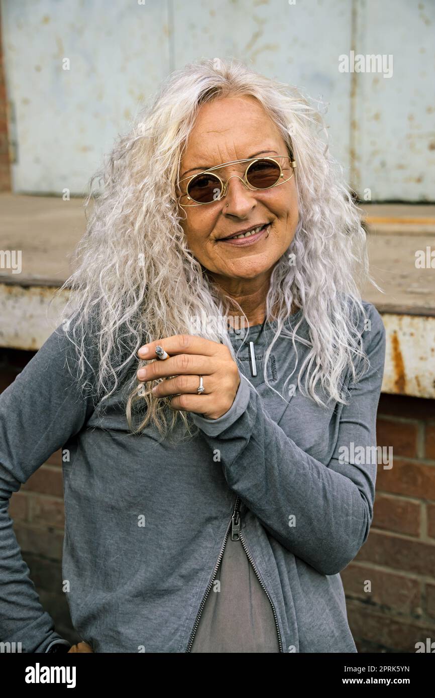 Beautiful woman with long bright curly hair is smoking a cigarette ...