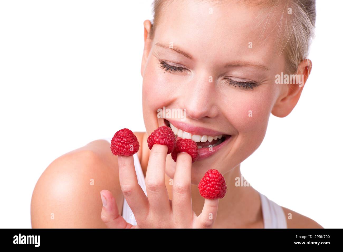 Tasty tips. a beautiful young woman playfully eating raspberries off ...