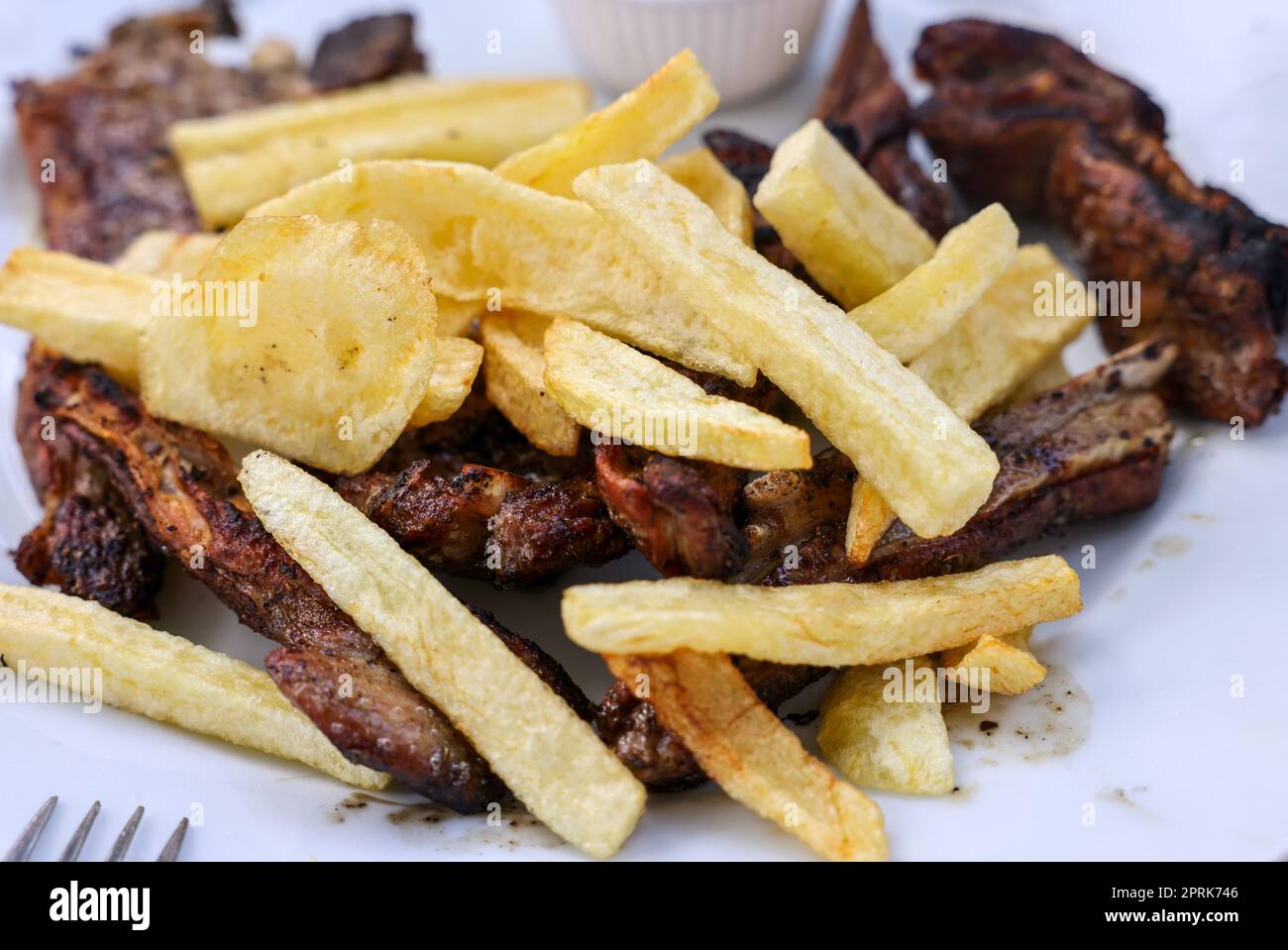 grilled goat with fries on a white plate Stock Photo - Alamy