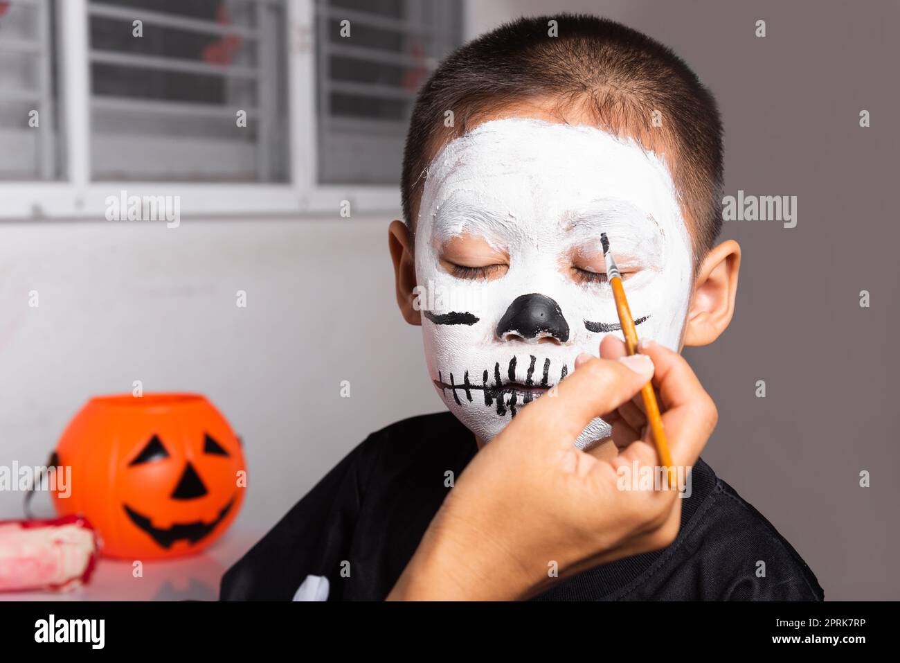 Portrait of woman applying color brush to child face for party at home ...