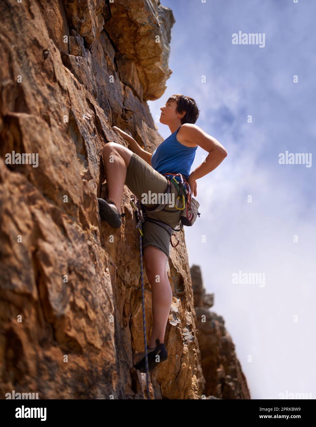 You need endurance to be a rock climber. a young woman scaling a rock ...