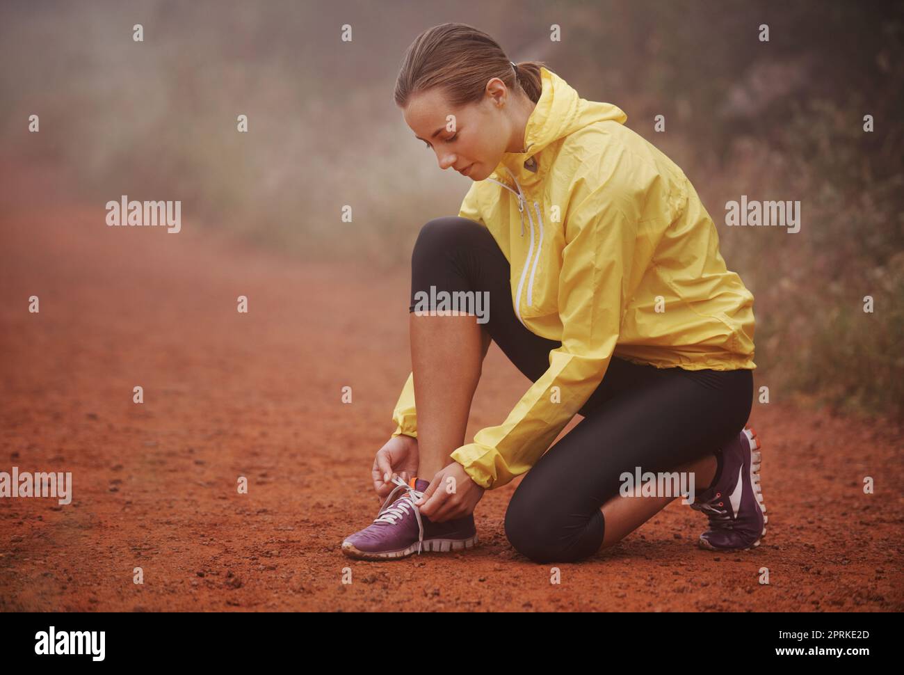Lacing up before her run. A young female runner tying her shoelaces while out training Stock ...