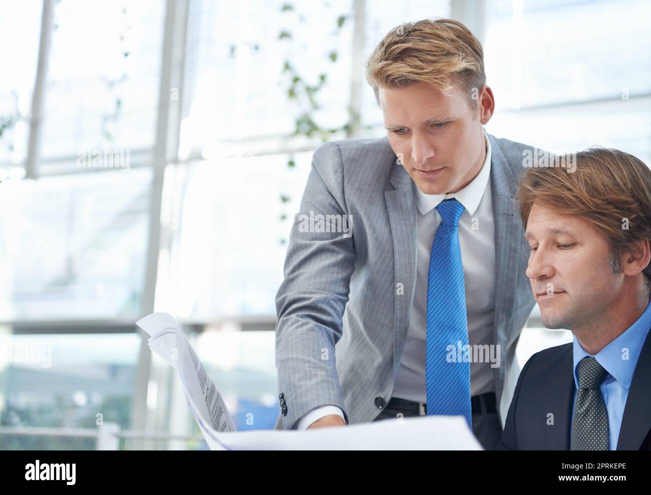 These plans look good. businesspeople looking over documents in a lobby ...