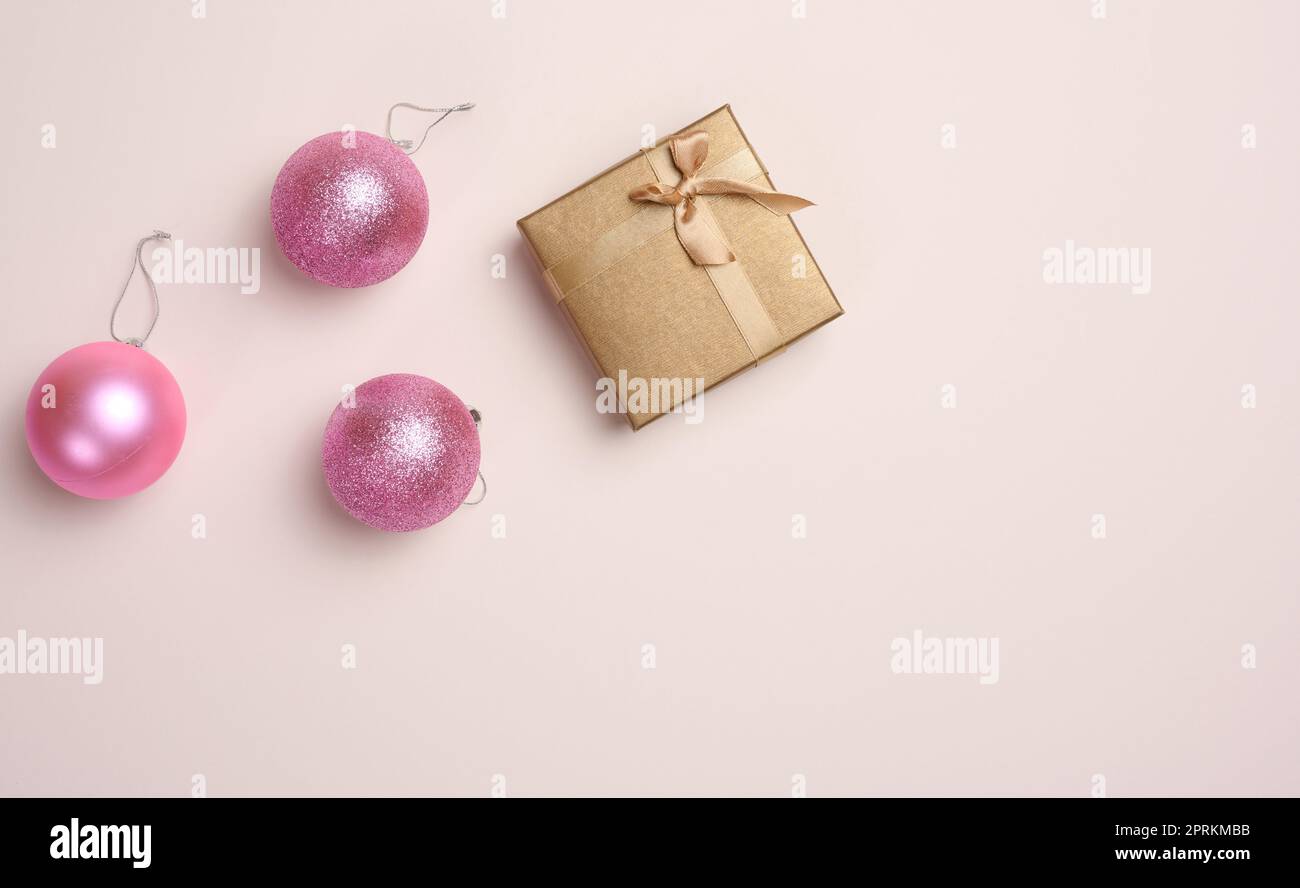 Pink shiny balloons and cardboard box with a gift on a beige background ...
