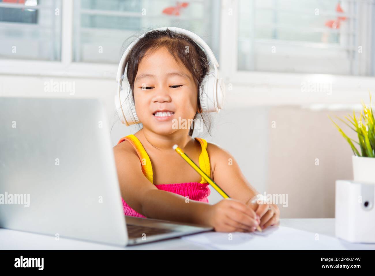 Little kid preschool wear headphone sit at desk use laptop computer and ...