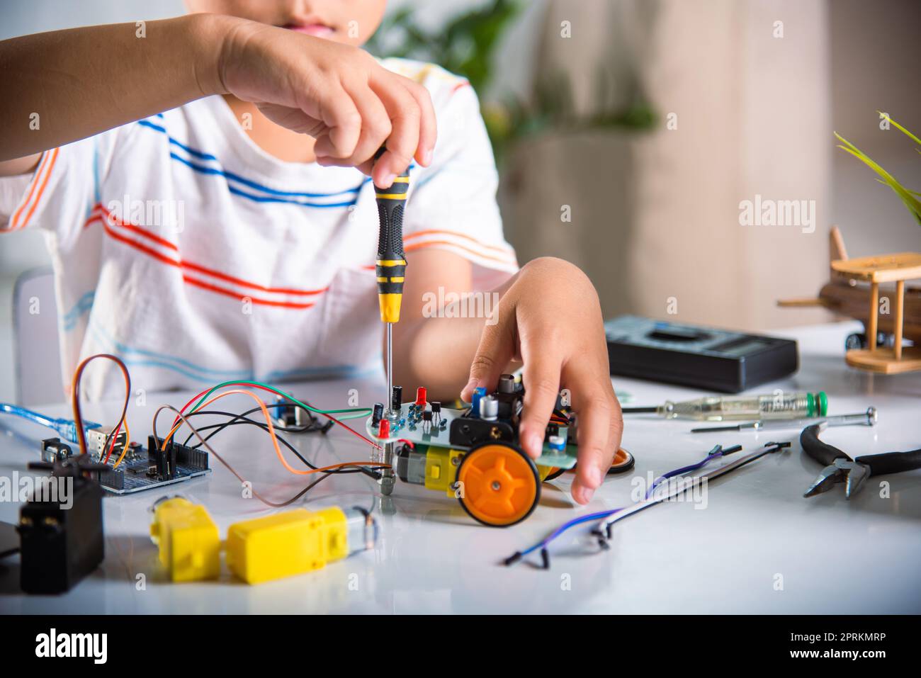 Little child tighten the nut with a screwdriver to assemble car toy ...