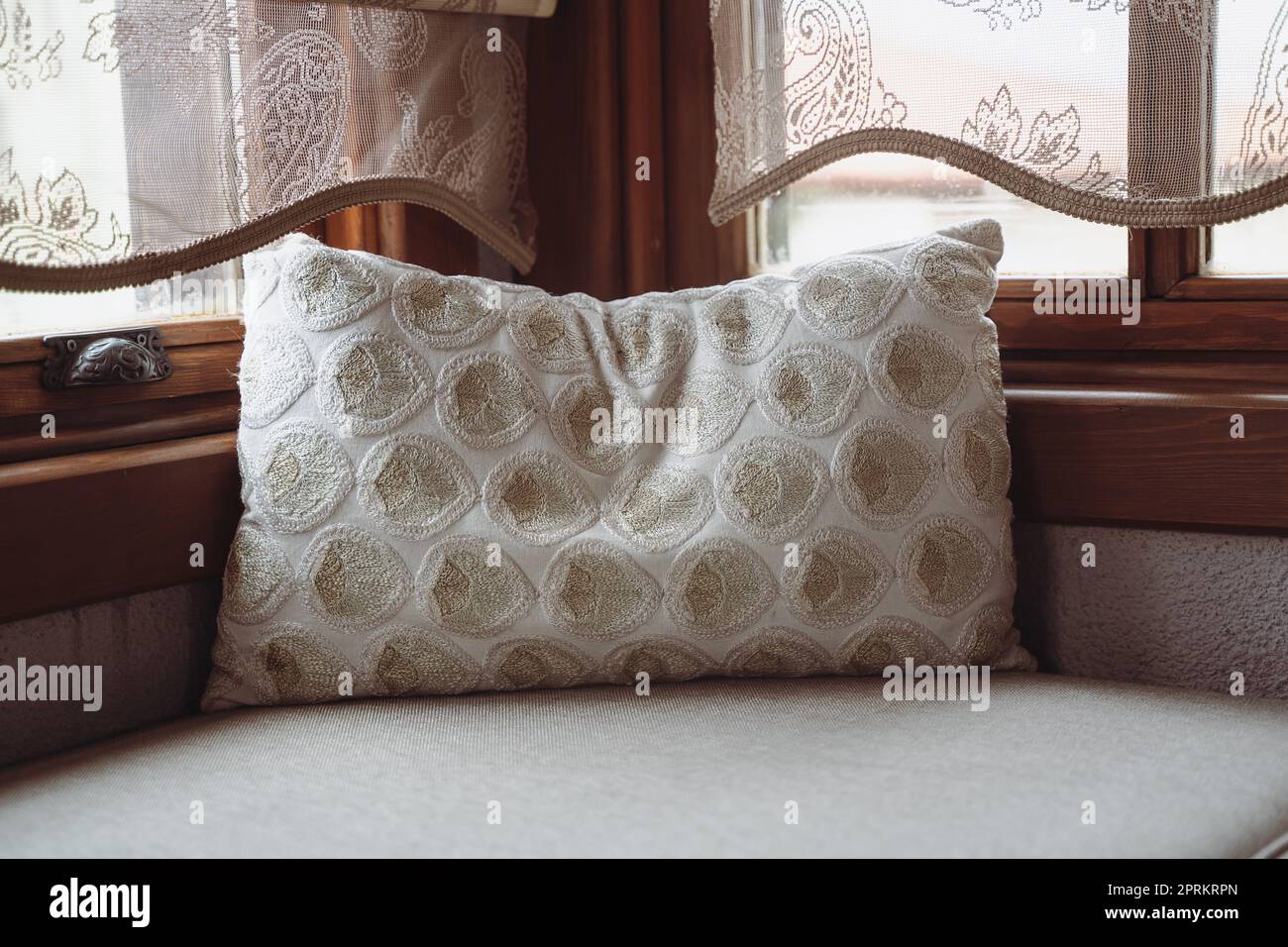 front view closeup of pillow with embroidery on divan in front of ...