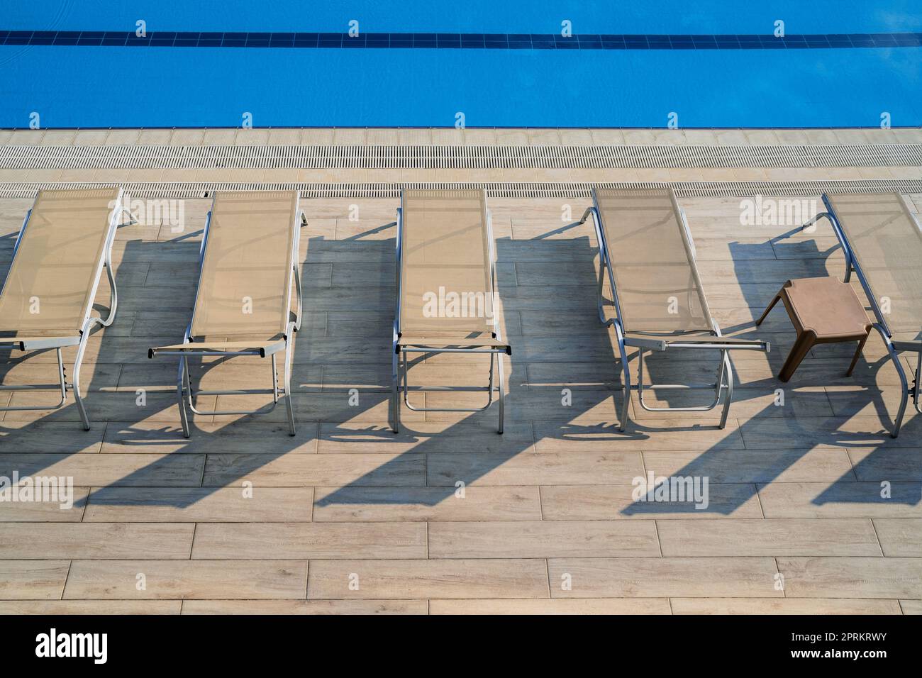 top view closeup of row of sunlounger chairs near a outdoor swimming ...