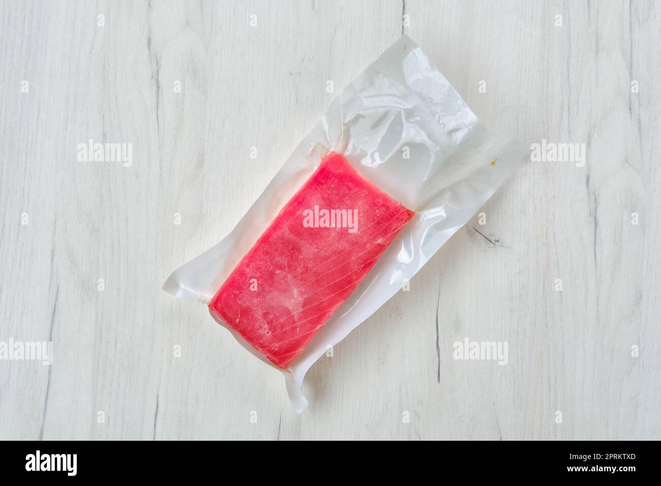 Raw frozen tuna fillet in vacuum packaging on wooden background Stock ...