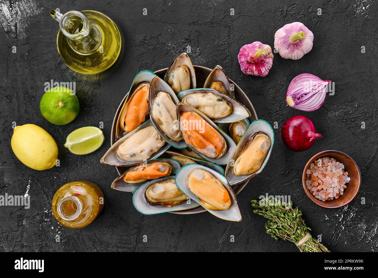 Plate with raw large mussels in half shell with spice on wooden table ...