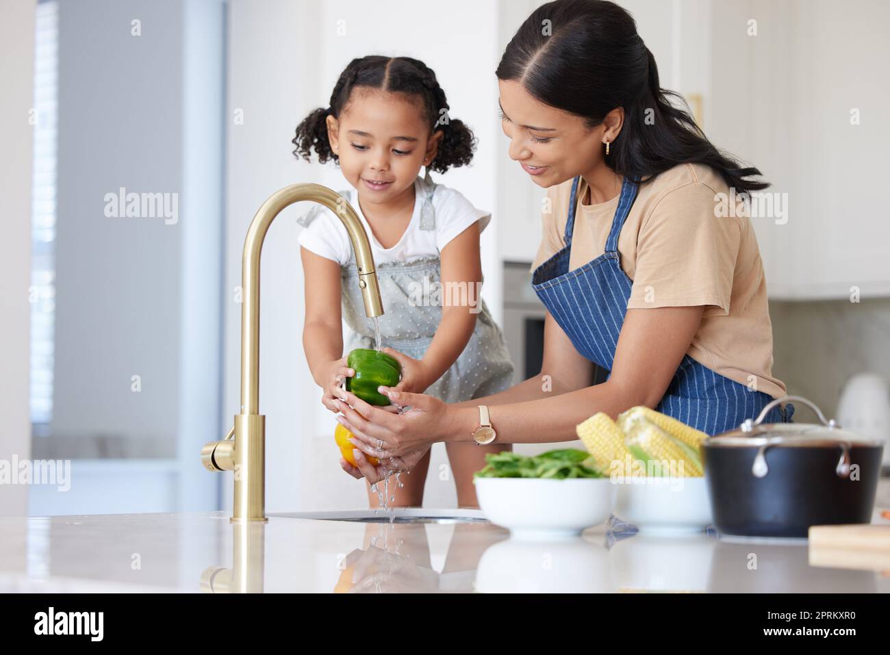 Kitchen, mother and child washing vegetable to cook dinner, lunch or ...