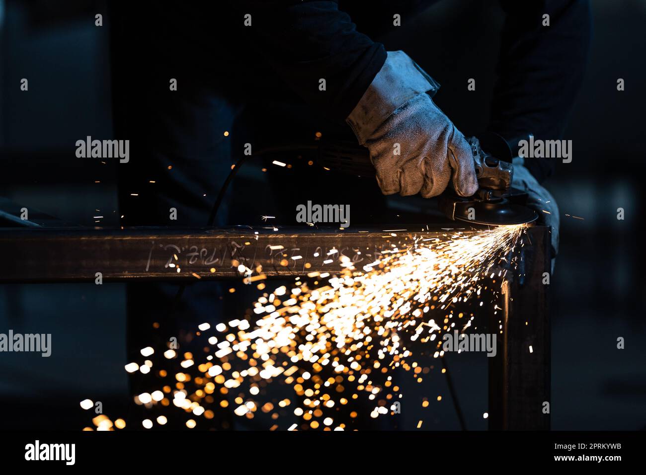 Man working on iron with grinder. Man at work. Sparkles and fire from ...