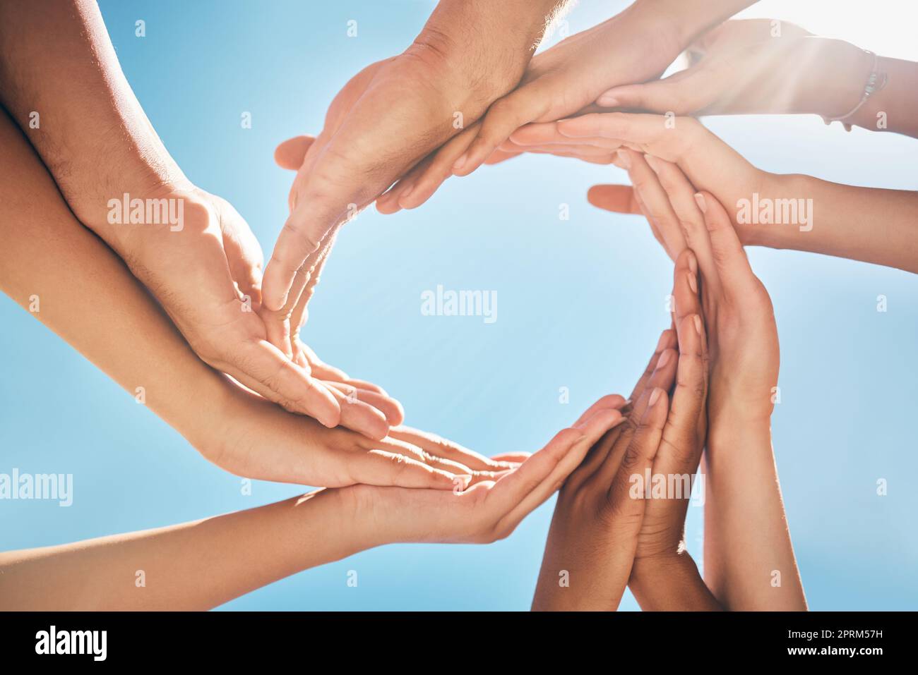 Circle, support and hands of friends for community, collaboration and trust against a blue sky ...