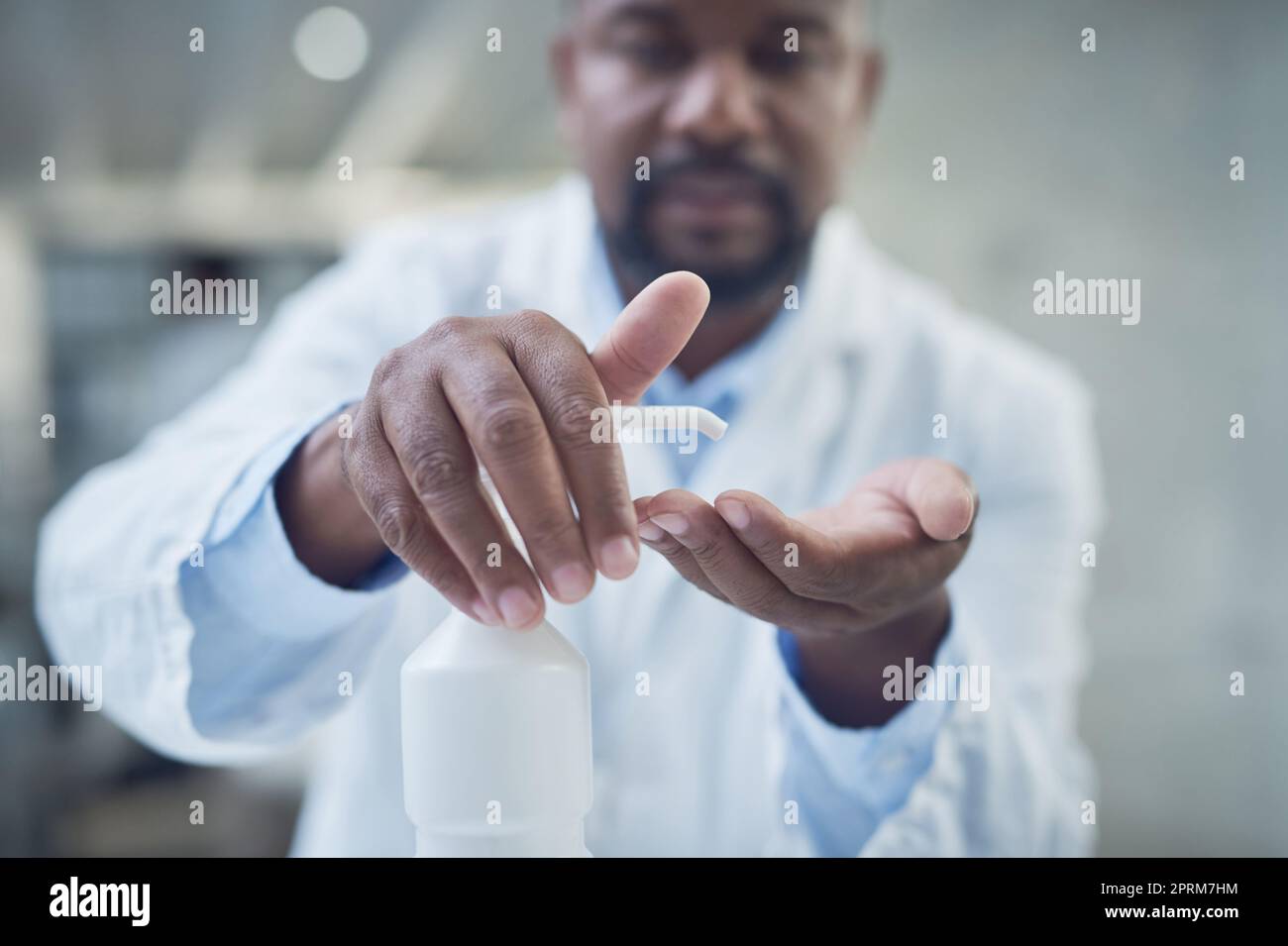 Safety comes first in this lab. a scientist disinfecting his hands ...