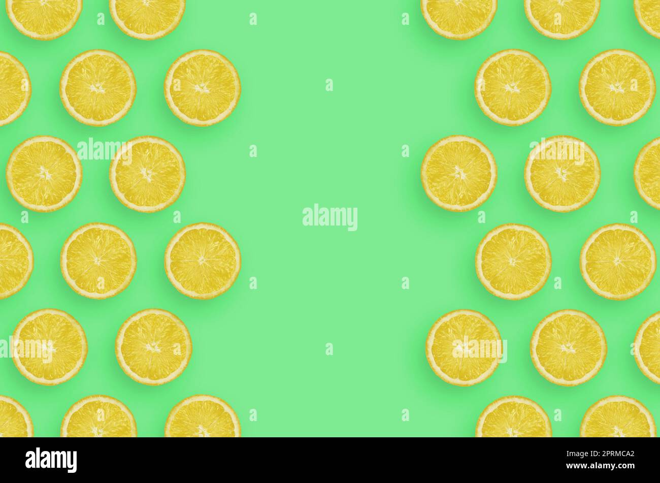Top view of yellow lemon fruit slices on bright green background. A ...