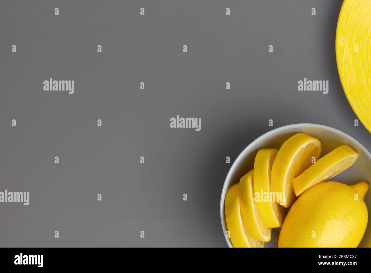 Yellow lemons in gray plate on gray background. Colors of the Year 2021 ...