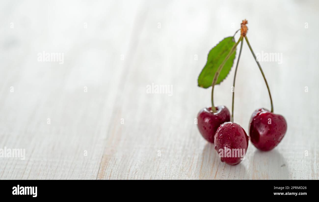 Cherry on white wooden background. Fresh ripe sweet cherry bunch with 3 ...