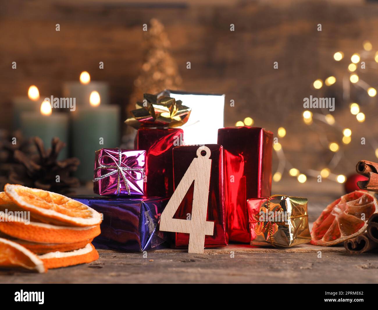 Candle of the fourth Advent burns, wooden number four with gift boxes ...