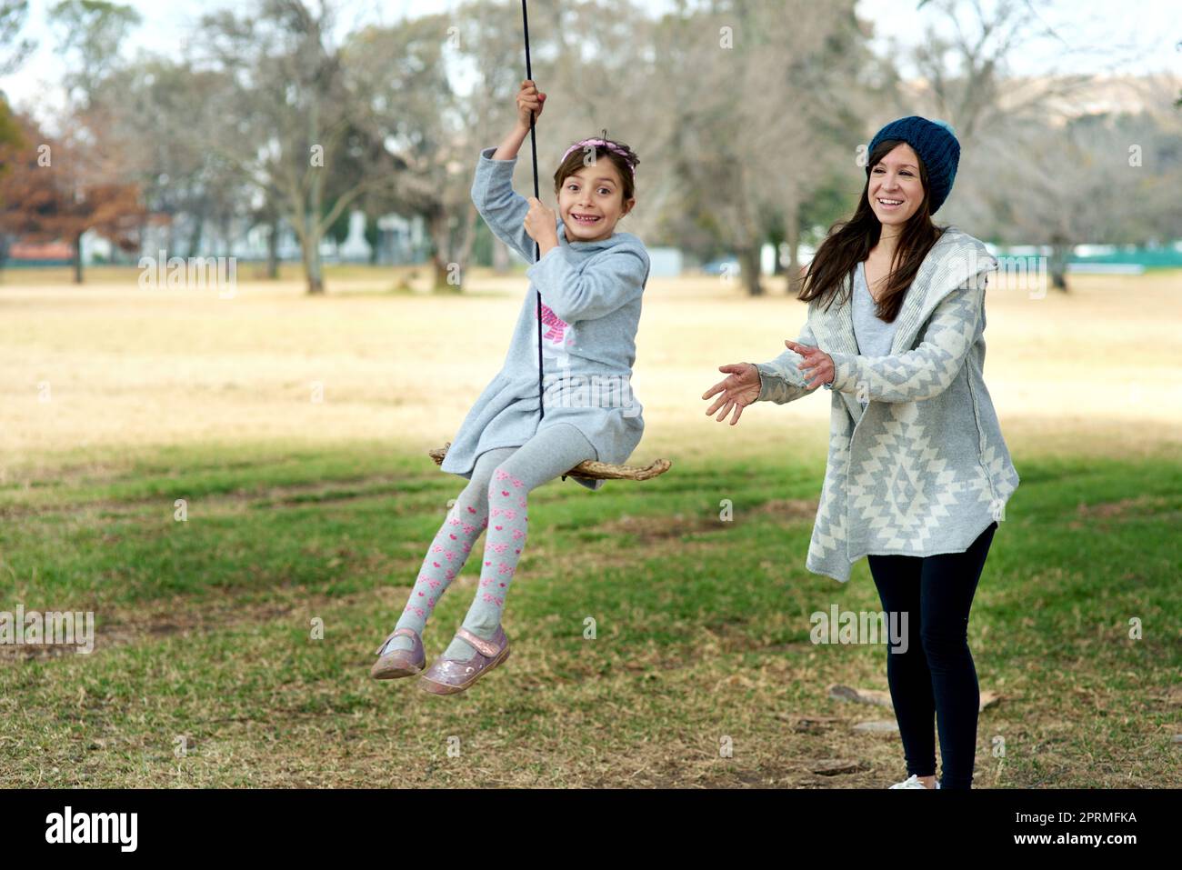 Swinging along to some fun times. a mother pushing her daughter on a swing at the park Stock ...