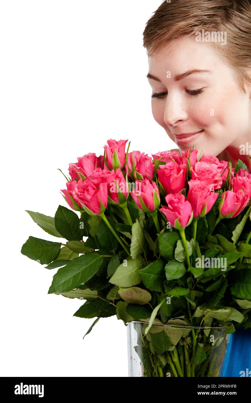 Stop and smell the roses. Studio shot of a young woman smelling a bunch ...