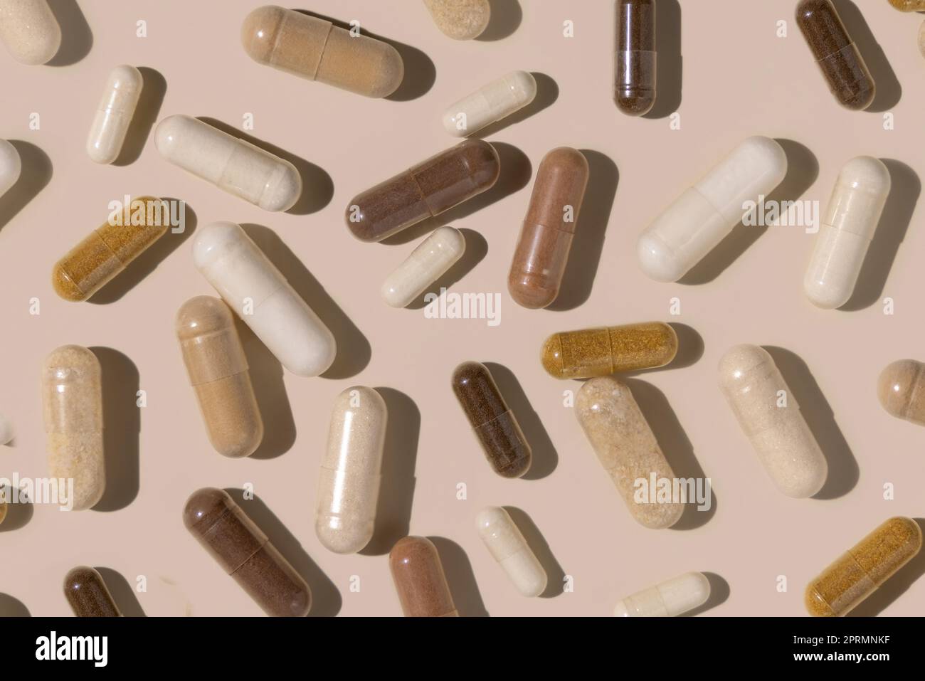 Mix of medical capsules on light beige top view, hard shadows. Taking ...