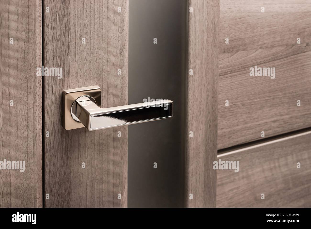 Close up of stylish silver chrome door handle on modern interior door ...