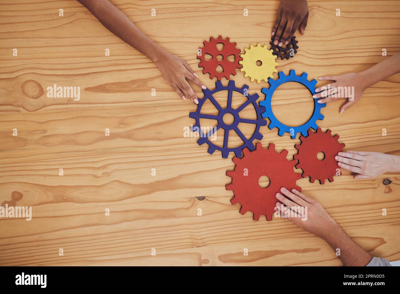 Success, collaboration and teamwork, people with gears on a wooden ...