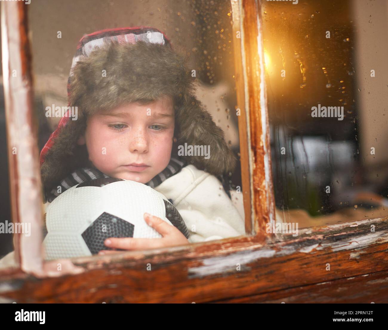 Hes got the rainy day blues. a sad little boy holding a soccer ball ...