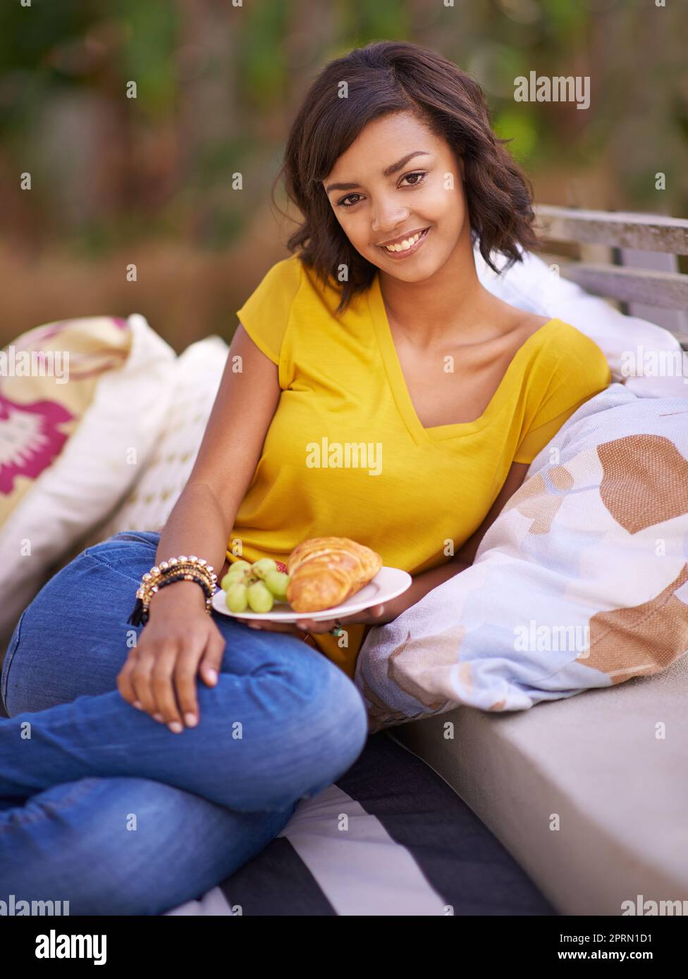 Brunch in the backyard. a young woman enjoying a snack in the backard ...