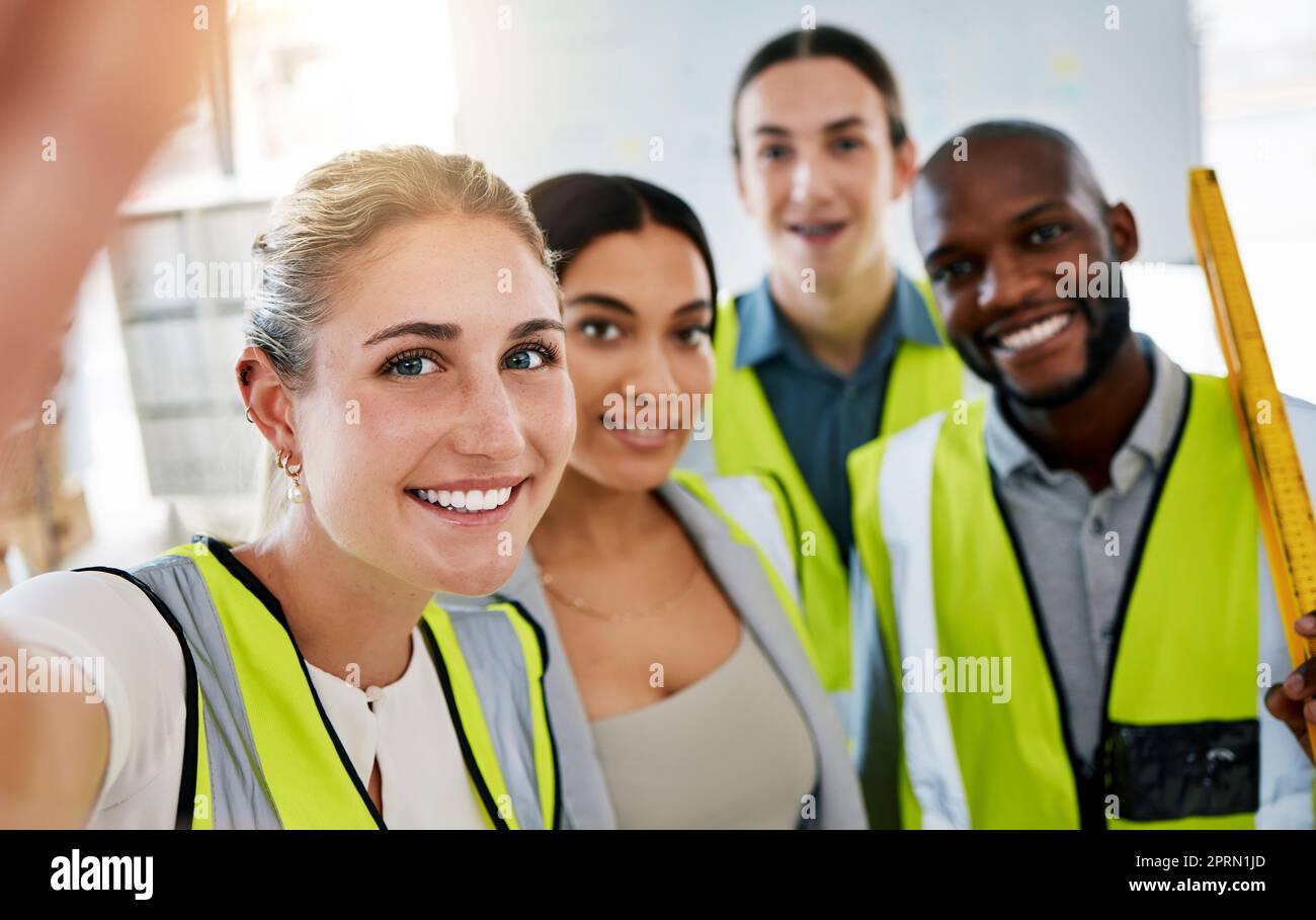 Group of industrial staff taking a selfie on a phone while working in a warehouse factory ...