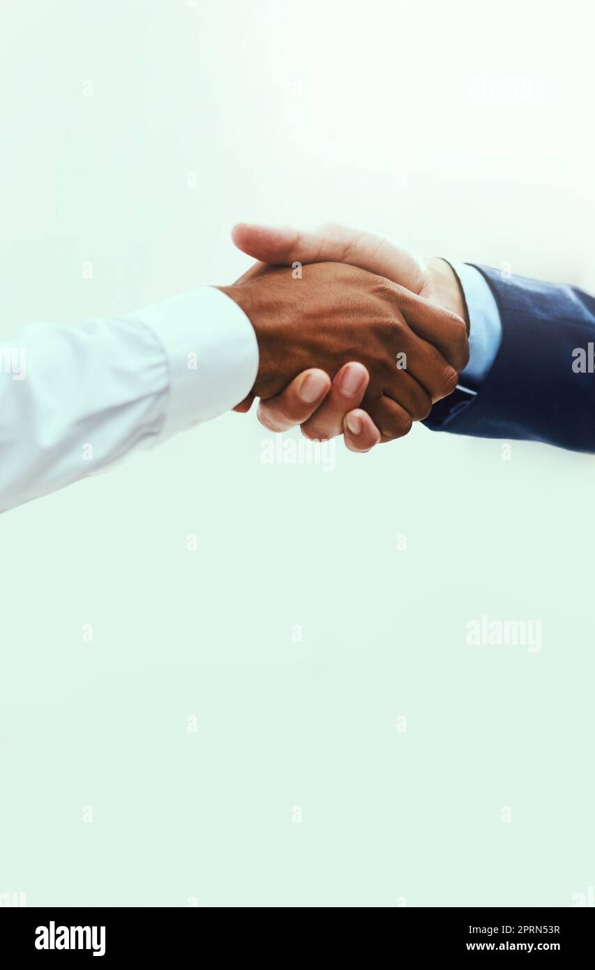 The deal is done. two unrecognisable businessmen shaking hands against ...