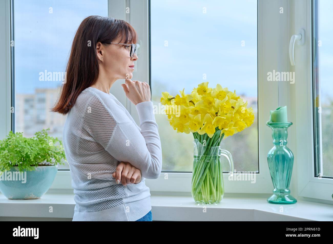 Middle-aged serious pensive woman looking out the window Stock Photo ...