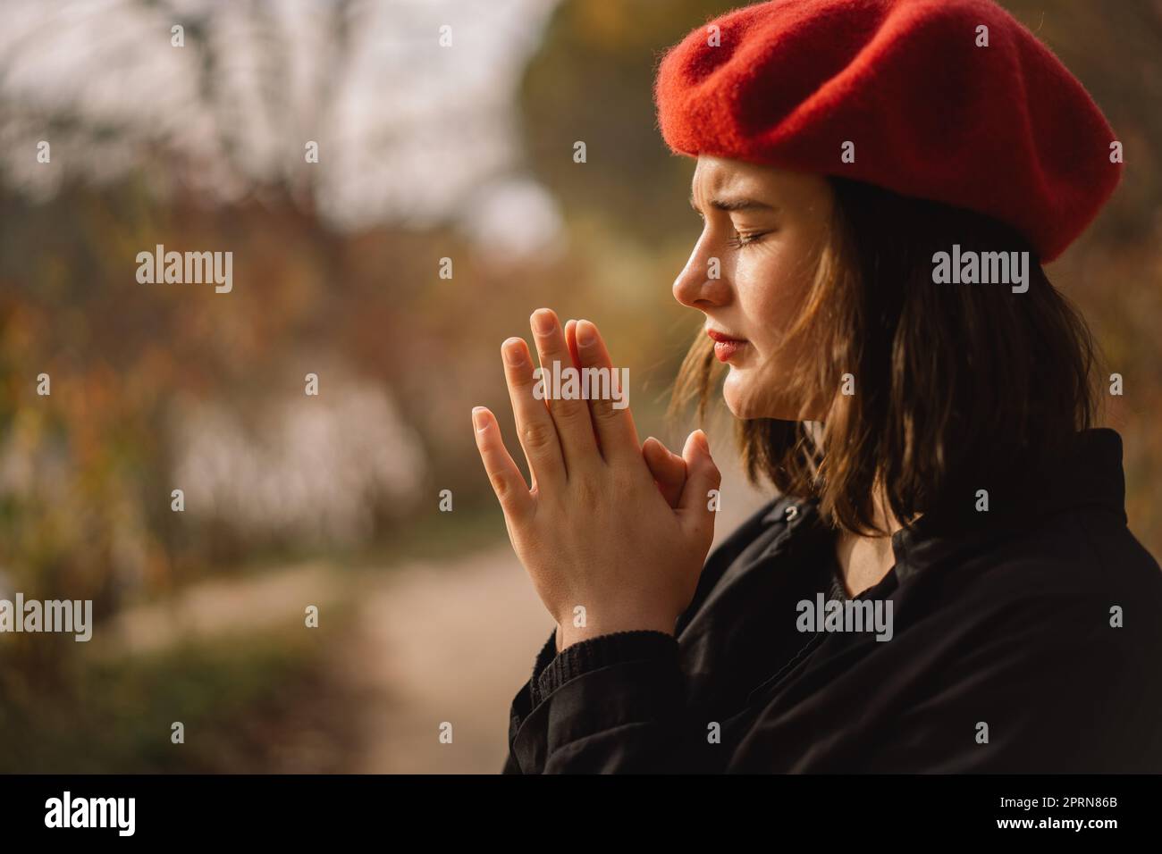 Teen girl closed her eyes and praying. Hands folded in prayer concept ...