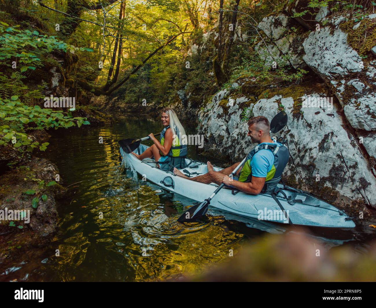 A young couple enjoying an idyllic kayak ride in the middle of a ...