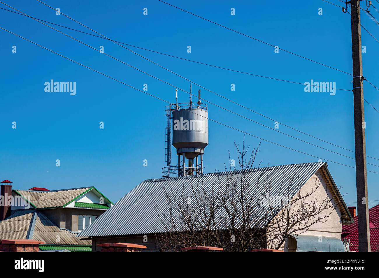 A water tower over the roofs of rural houses against the blue sky ...