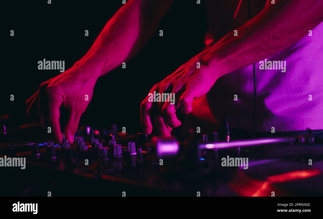 Hands of a disc jockey mixing music with a sound mixer device. Disc ...