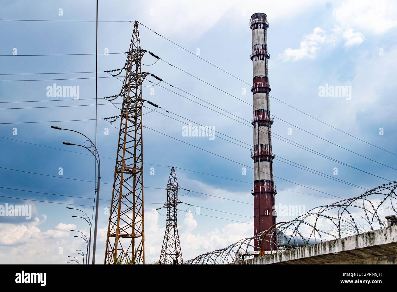 High voltage tower with wires and industrial chimney. High-voltage ...
