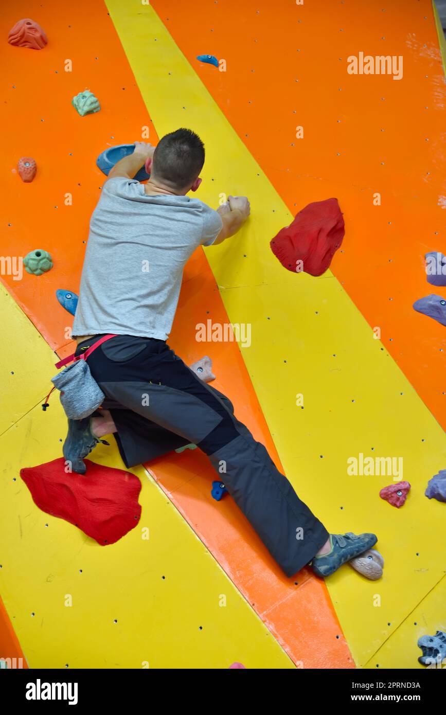 Young Man Climbing Up On Practice Wall In Gym Stock Photo - Alamy