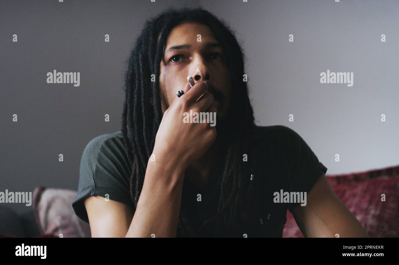 What is he thinking. a young man smoking a marijuana joint at home ...